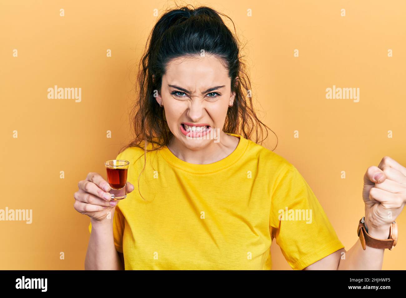 Young hispanic woman drinking whiskey shot annoyed and frustrated ...