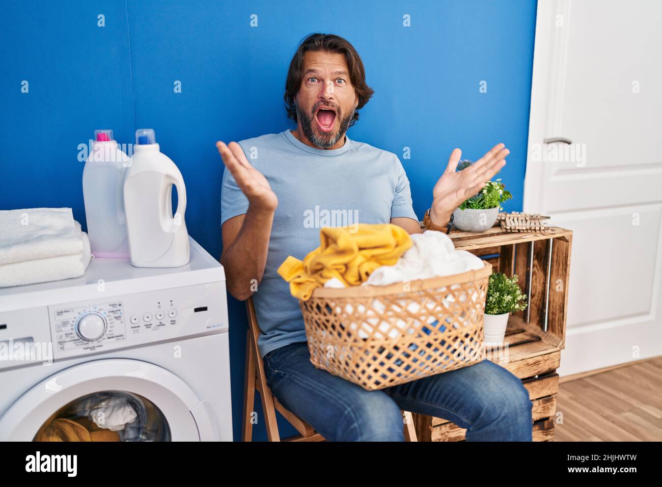 Handsome middle age man waiting for laundry celebrating crazy and ...