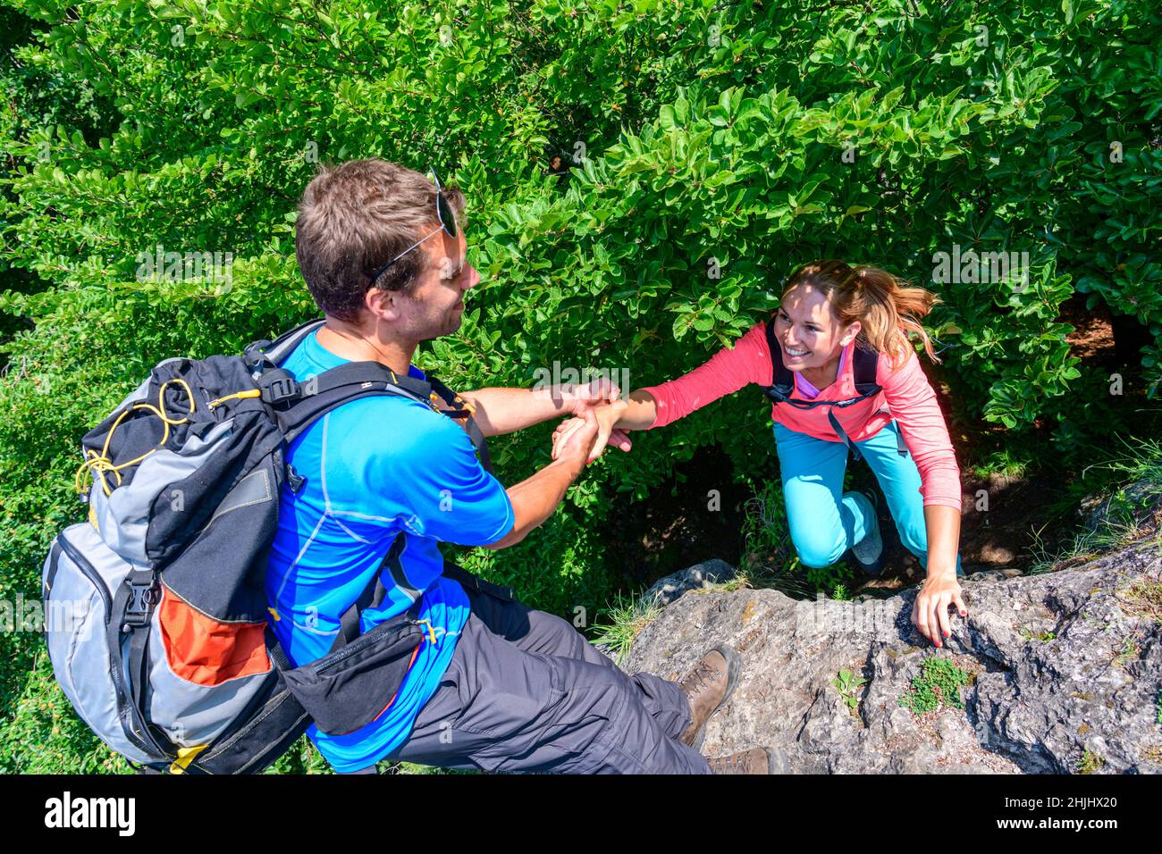 Man helping woman to climb up in rocky nature Stock Photo - Alamy