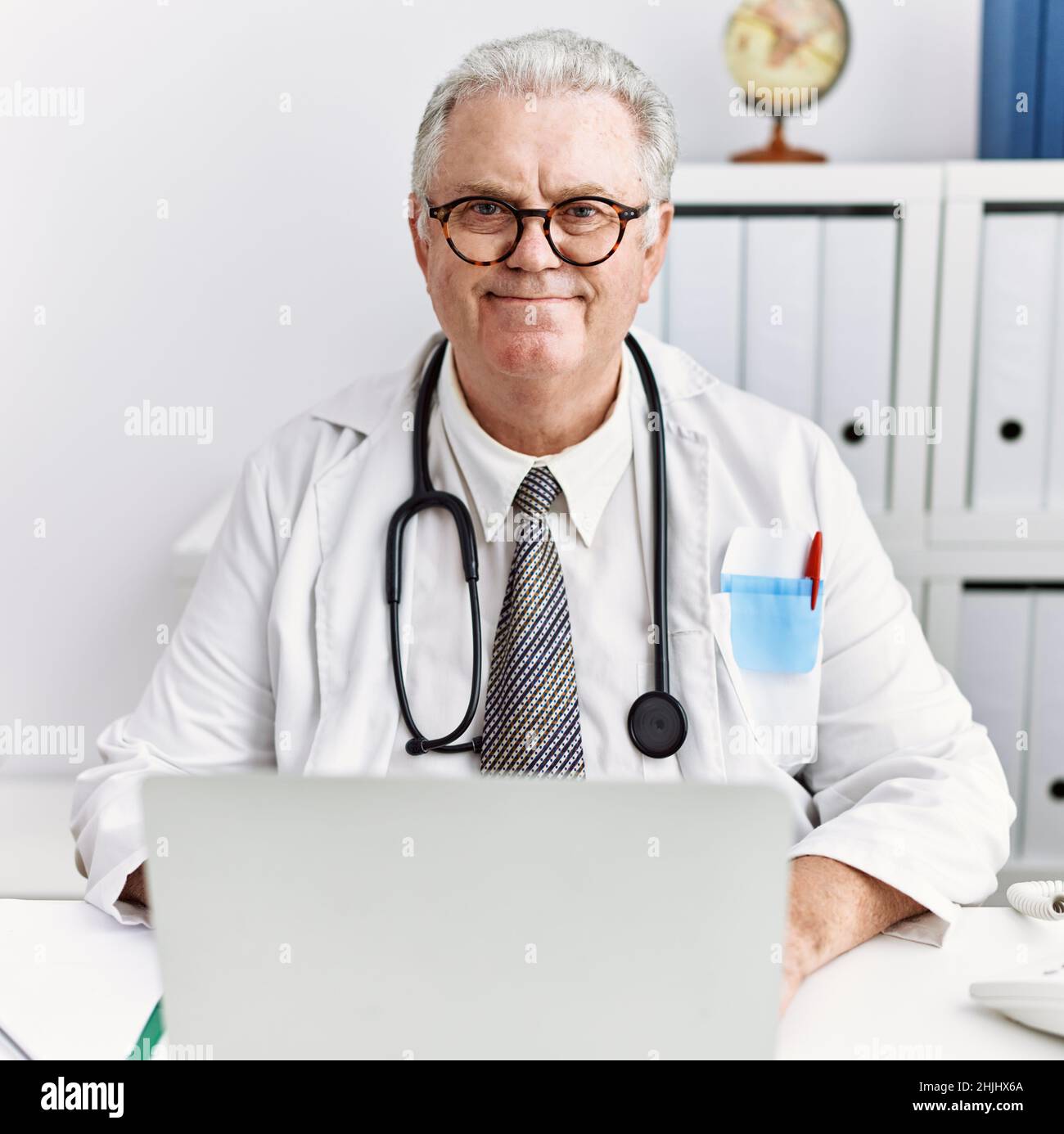 Senior caucasian man wearing doctor uniform and stethoscope at the ...