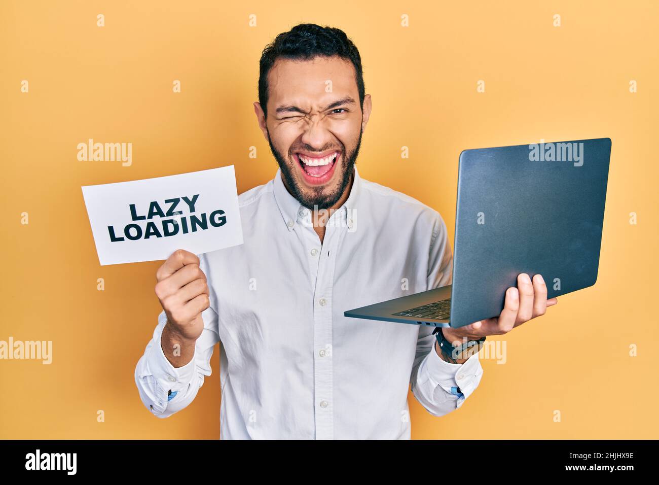 Hispanic man with beard working using computer laptop holding lazy ...