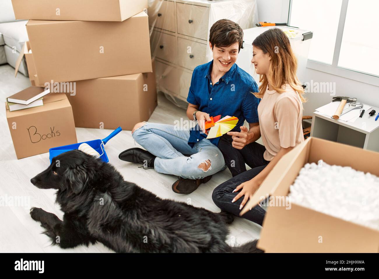 Young caucasian couple smiling happy sitting on the floor with dog ...