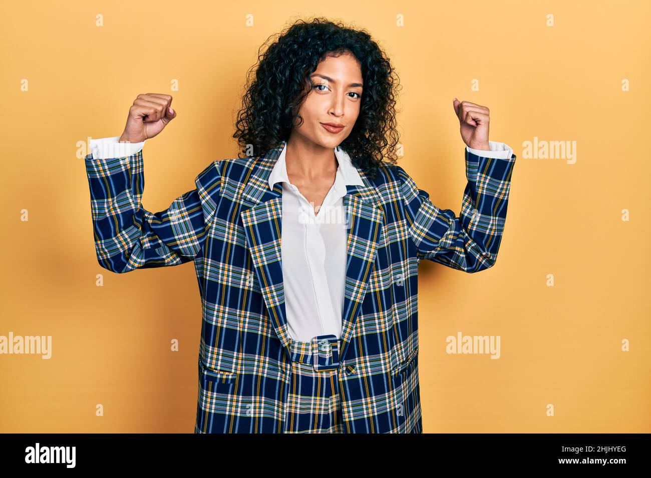 Young latin girl wearing business clothes showing arms muscles smiling ...