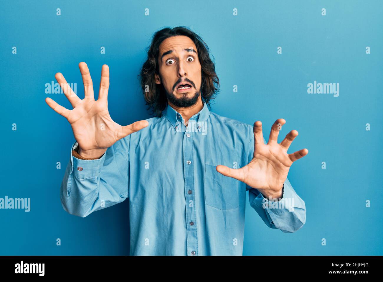 Young hispanic man wearing casual clothes afraid and terrified with ...