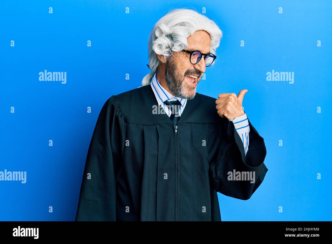 Middle age hispanic man wearing judge uniform pointing thumb up to the ...