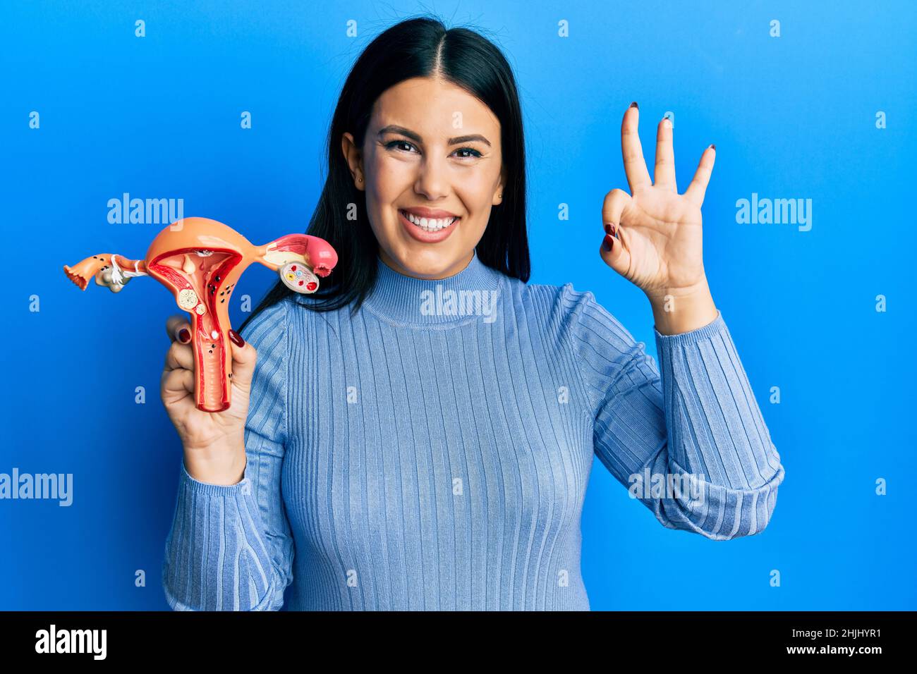 Beautiful brunette woman holding anatomical model of female genital ...
