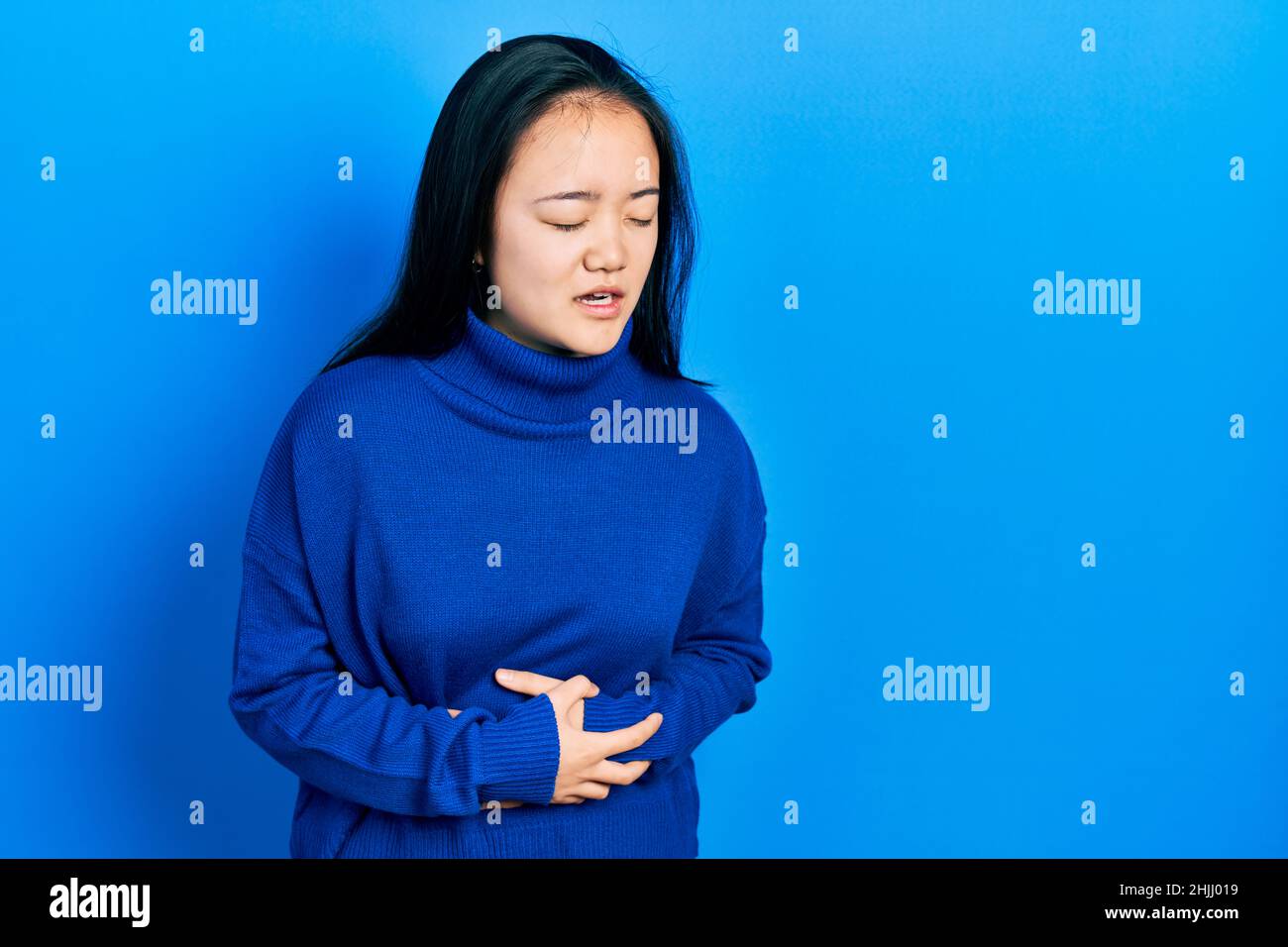 Young chinese girl wearing casual clothes with hand on stomach because ...