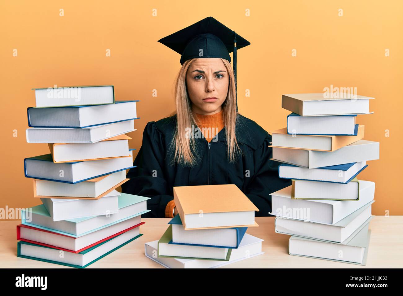 Young caucasian woman wearing graduation ceremony robe sitting on the ...