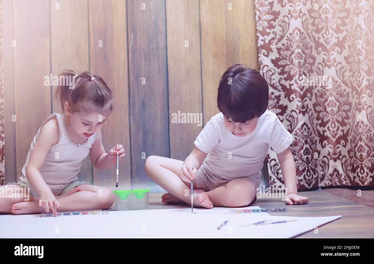 Little children paint on a large sheet of paper on the floor Stock ...