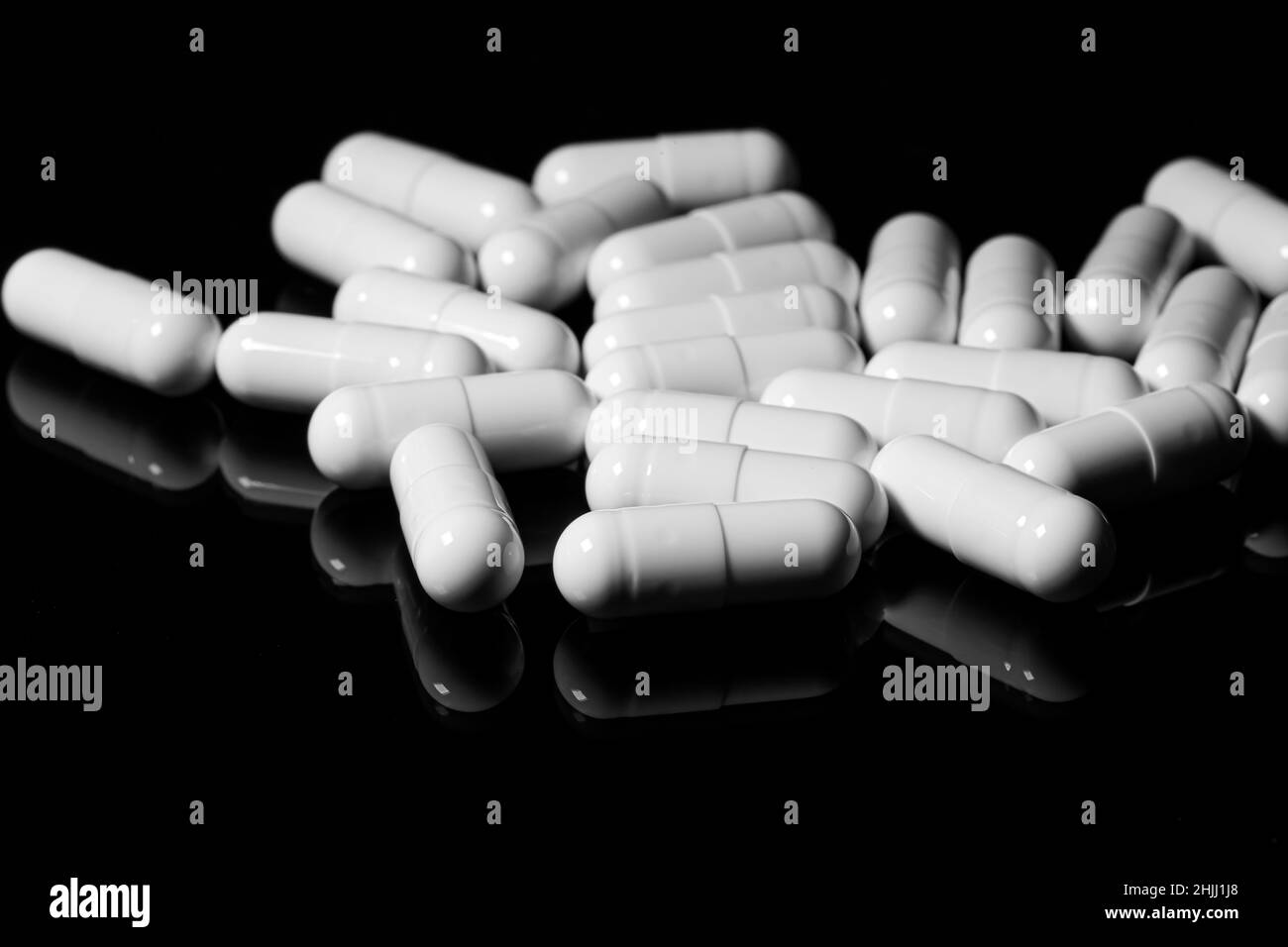 Macro Close up of white painkiller capsule on a reflective black ...