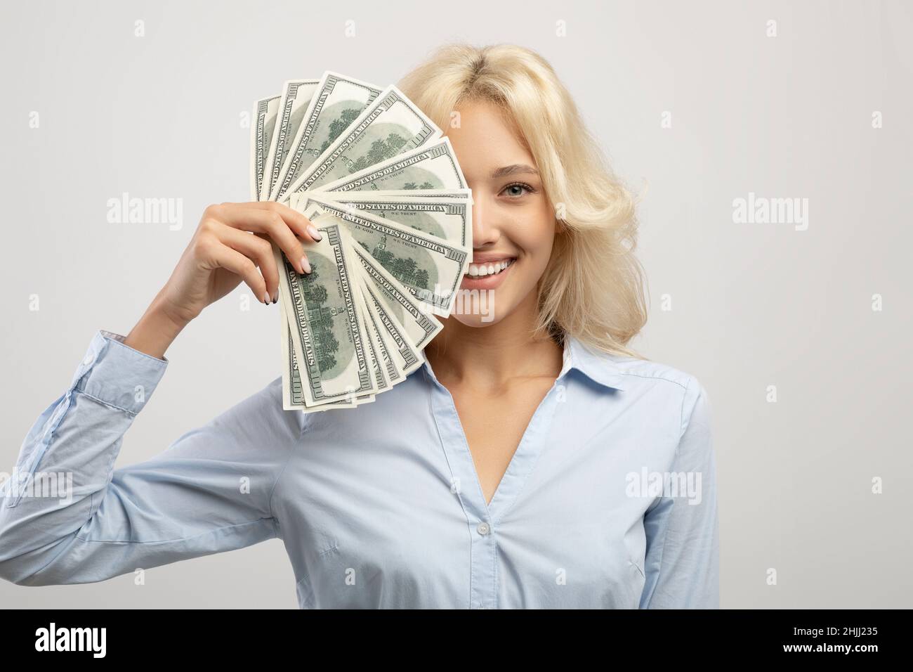 Portrait of happy business lady hiding face behind cash, holding bunch ...