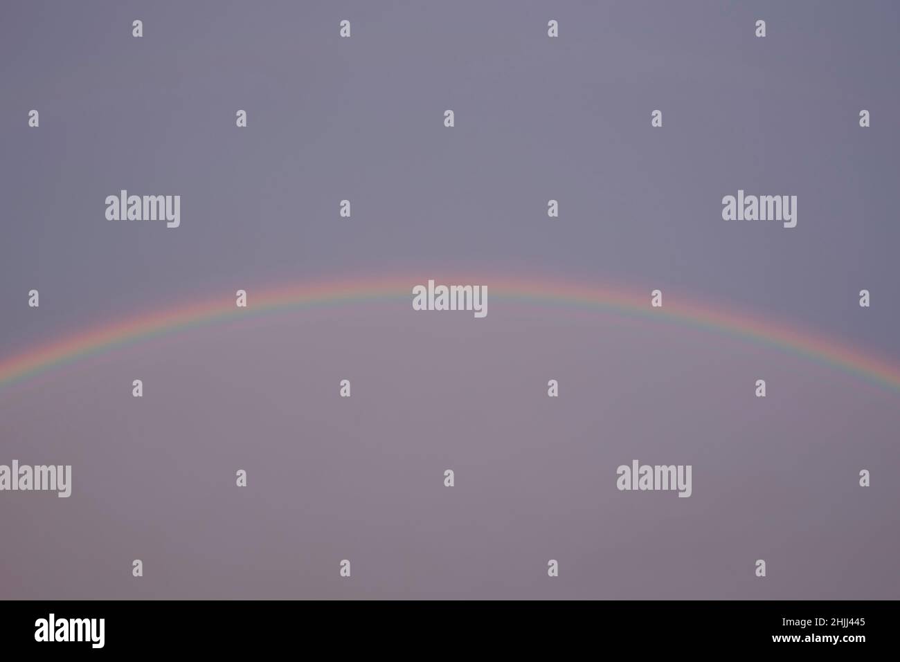 the spectral colors of a rainbow in a gray sky in summer Stock Photo ...