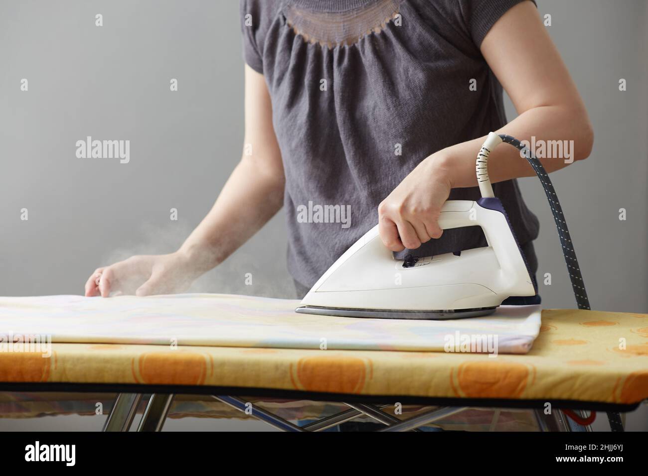 female hands are holding a white iron and iron on an ironing board ...