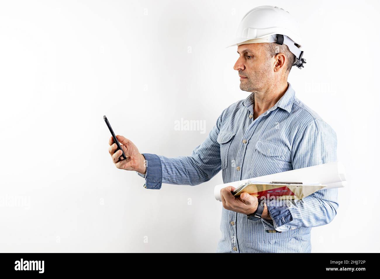 Male civil engineer with blueprints in a white hard helmet. Middle-aged ...