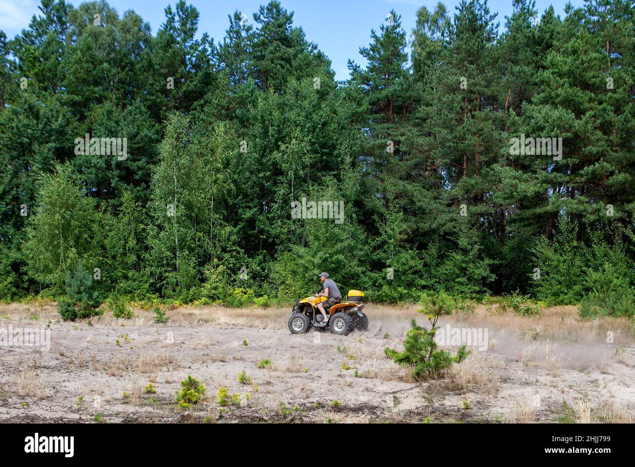 Kyiv- September 2019 Man riding a yellow quad ATV all terrain vehicle ...