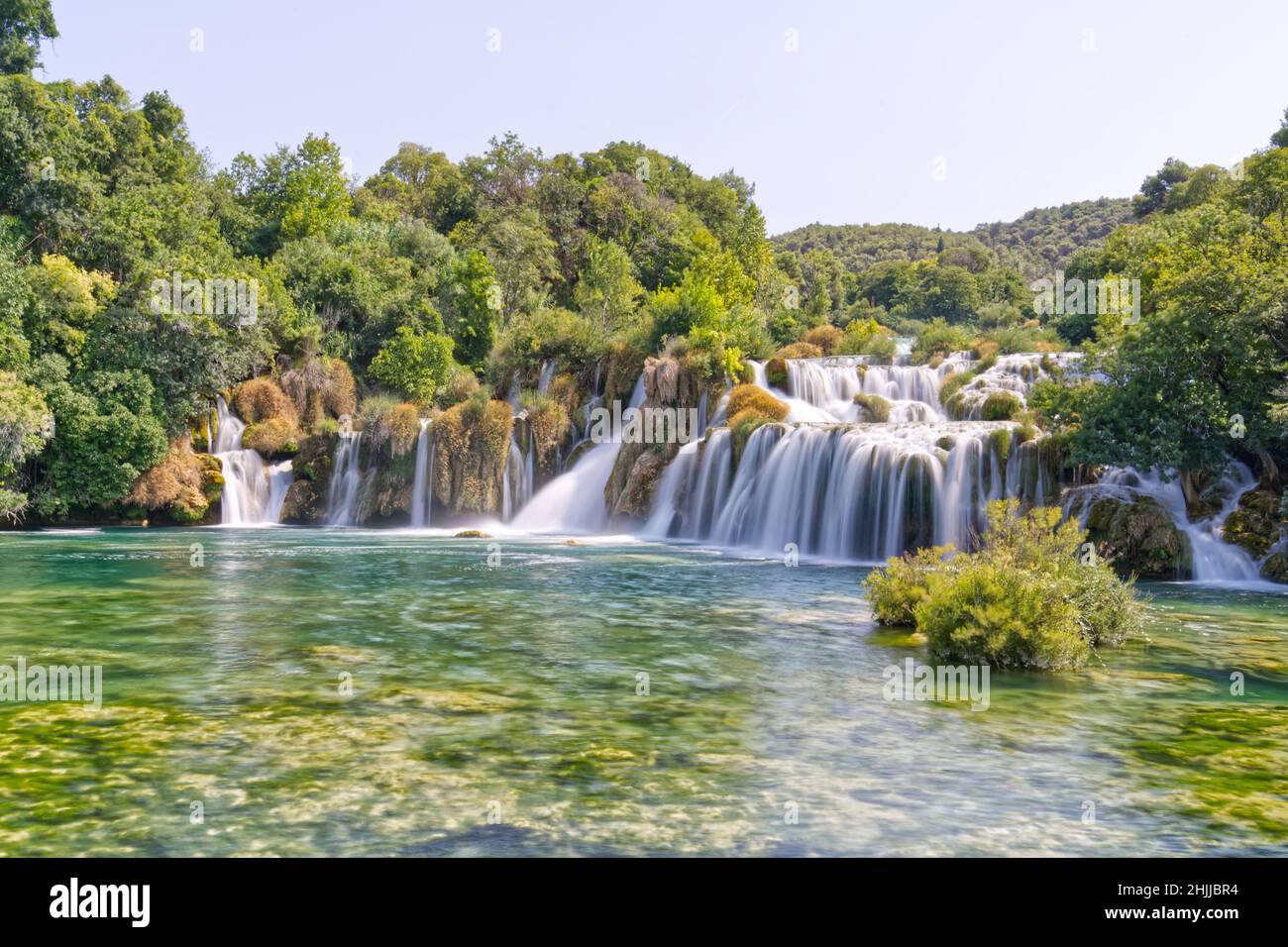 Natural view of a beautiful waterfall and forest under a bright sunny ...