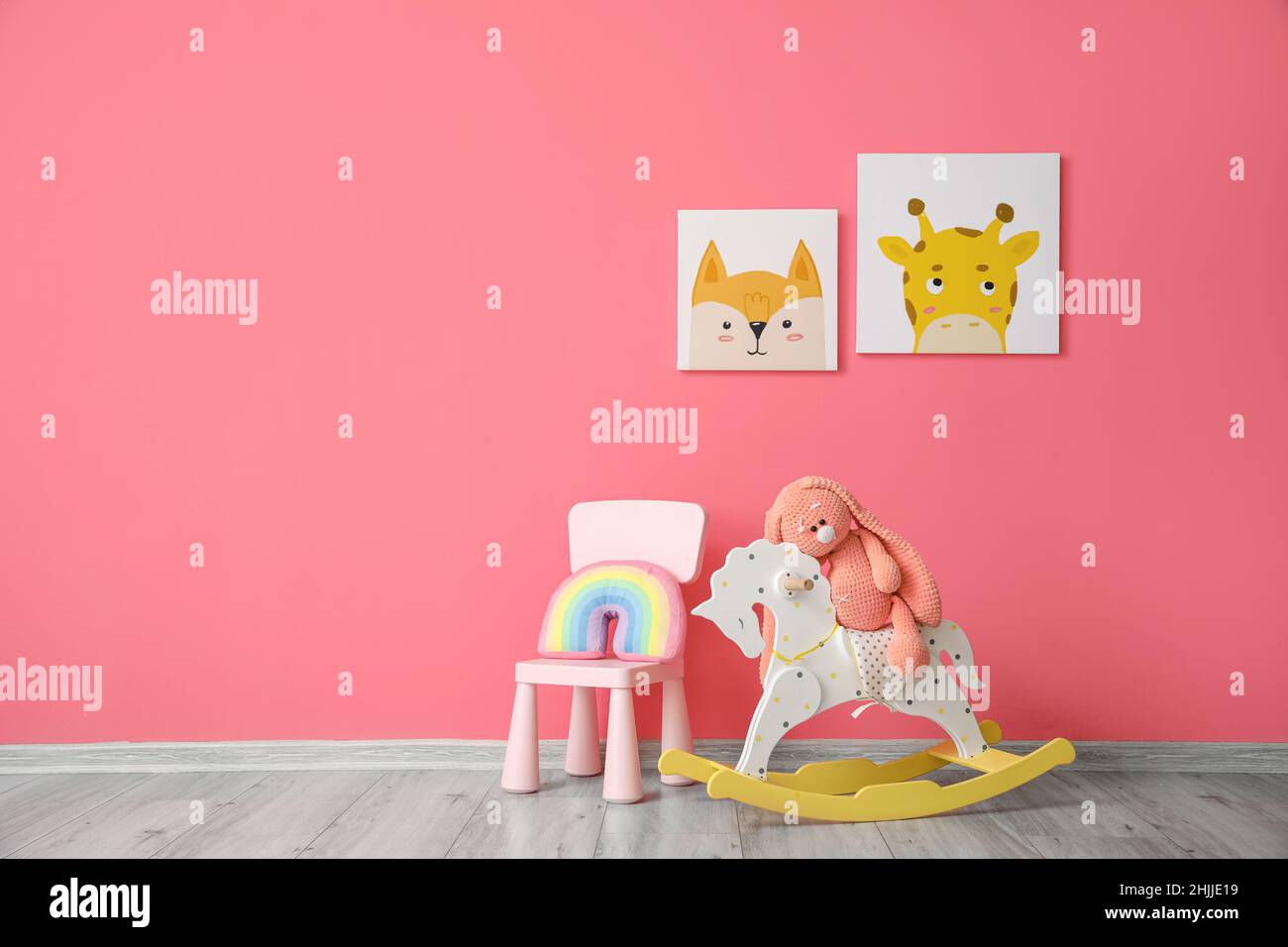 Cute rabbit sitting on rocking horse and chair with rainbow toy near ...