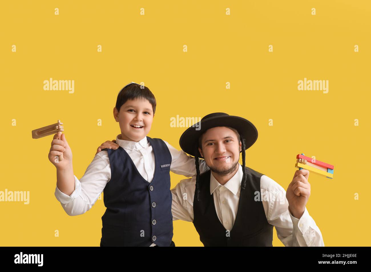 Happy Jewish man and boy with graggers for Purim holiday on color ...