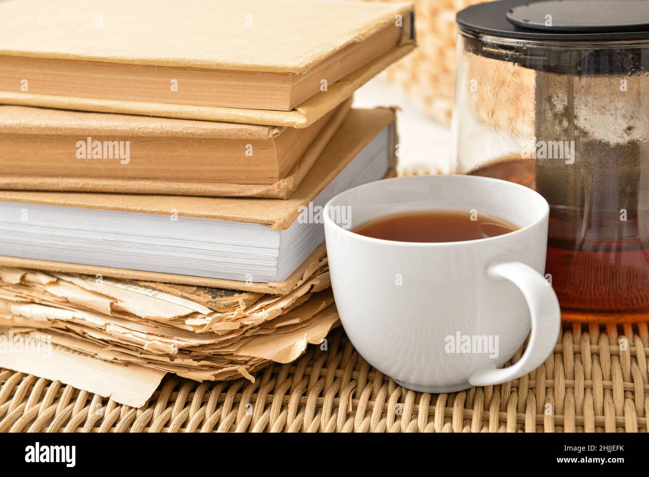 Stack of books with cup and teapot on wicker tray, closeup Stock Photo ...