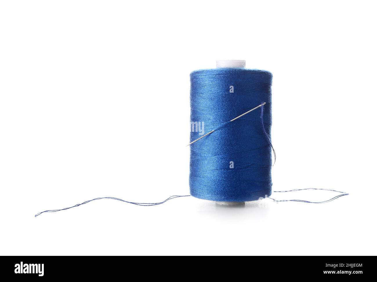Blue sewing thread spool and needle on white background Stock Photo - Alamy