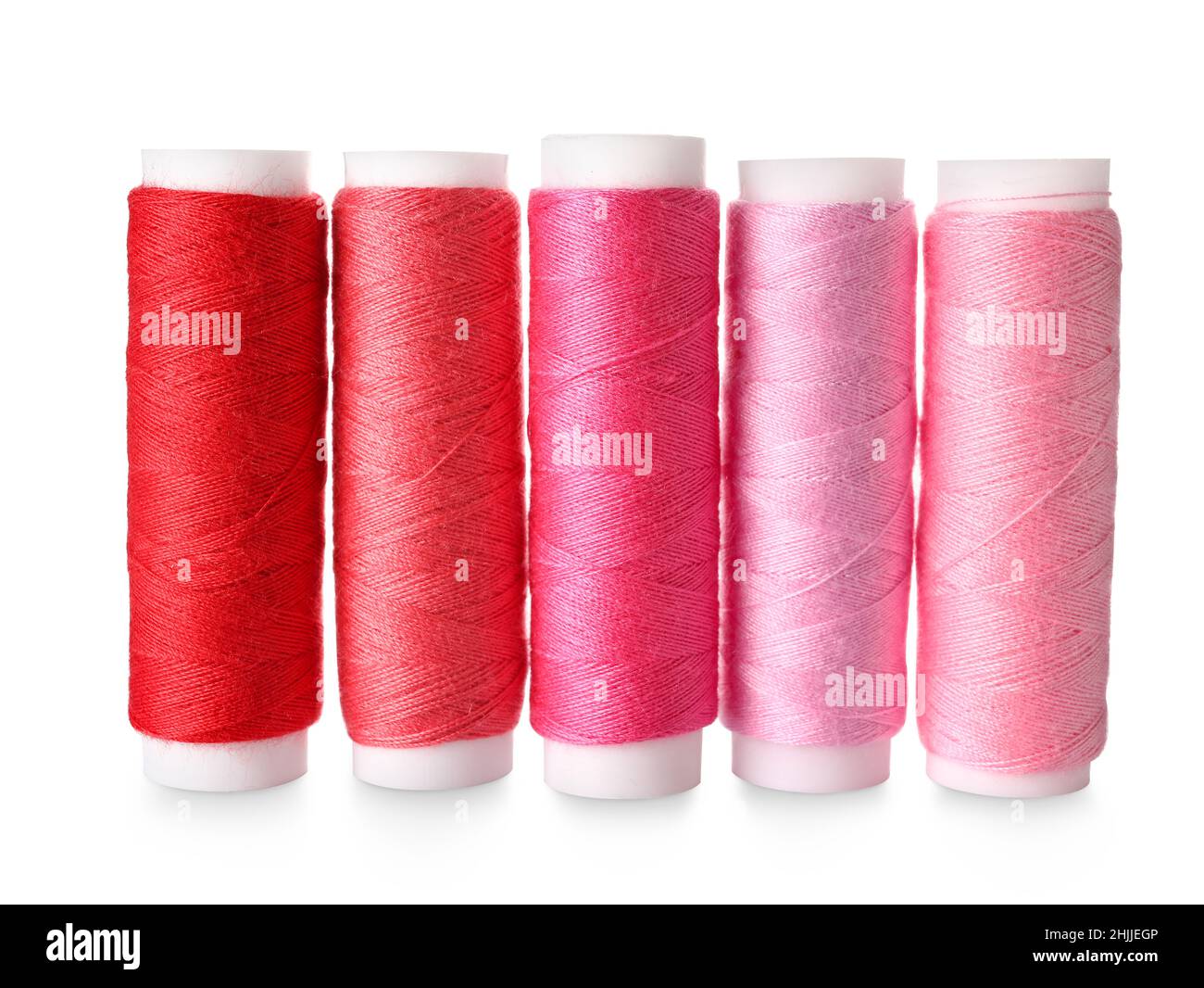 Pink and red sewing thread spools on white background Stock Photo - Alamy