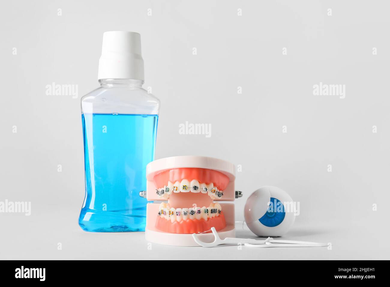 Model of jaw with braces, toothpicks, floss and mouthwash on white ...