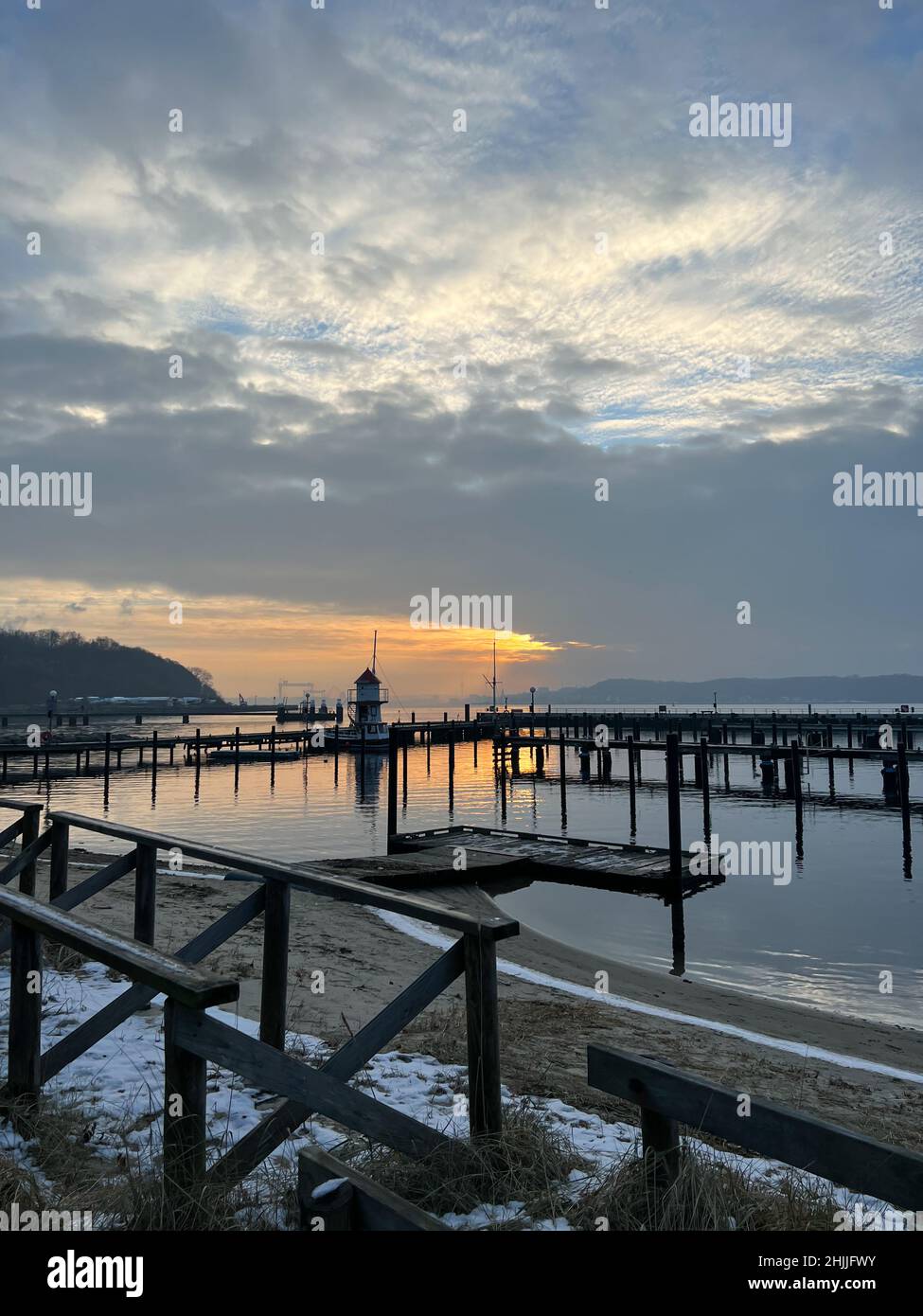 Sunset scene over Baltic sea with empty harbor and small lighthouse ...
