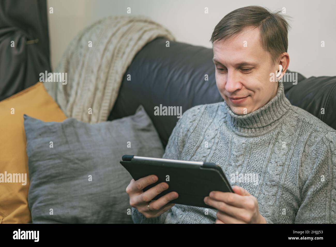 Handsome man using a digital tablet while resting on couch at home ...
