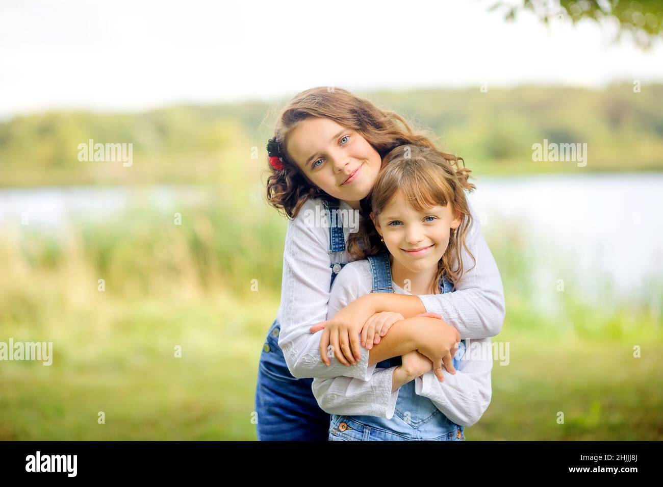 Happy little girls hug and pose in the park. Children relax and play ...