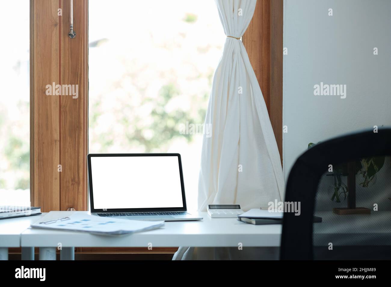 Mockup laptop with blank screen on white table with calculator and ...