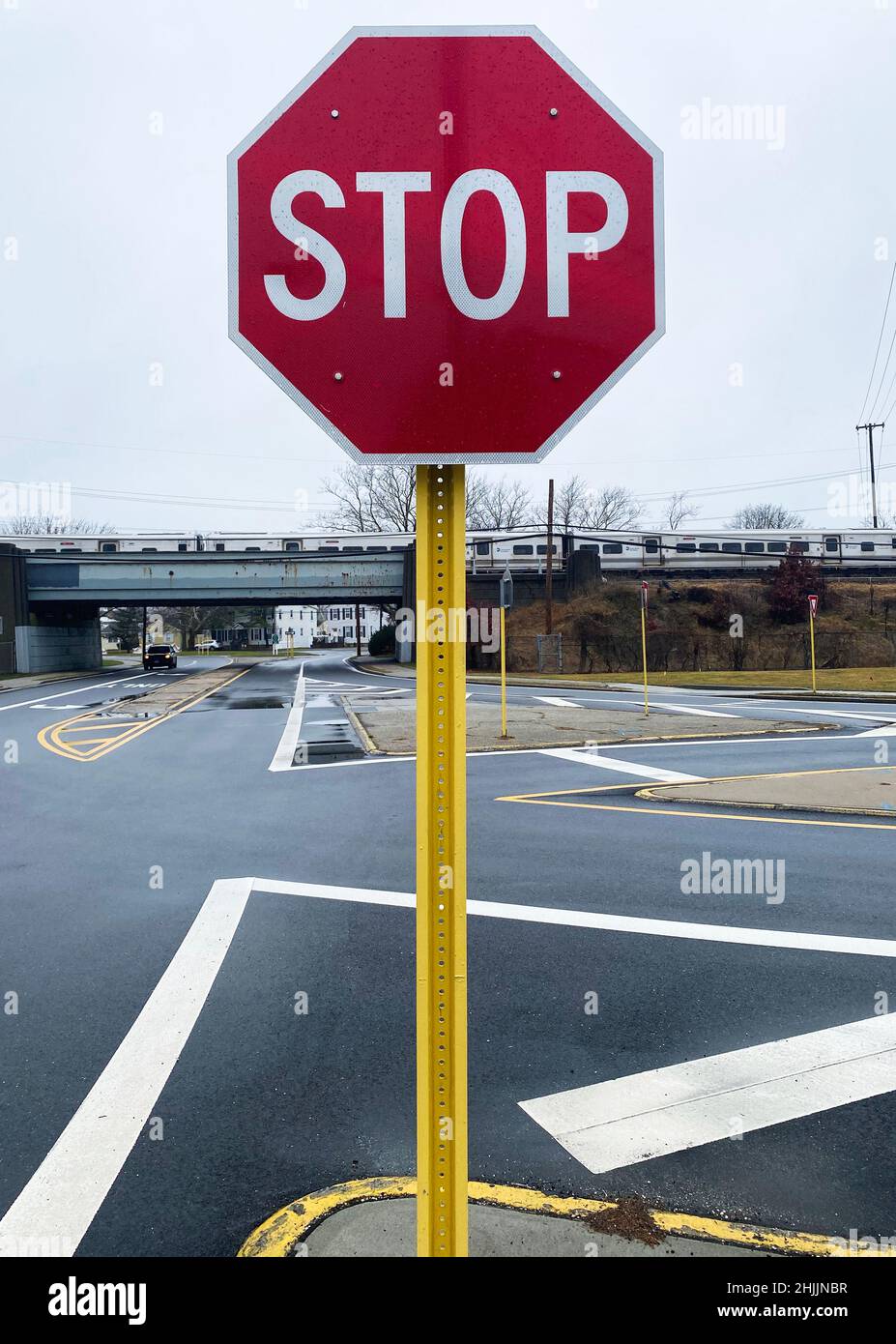 Red stop sign by active intersection with train trestle in background ...