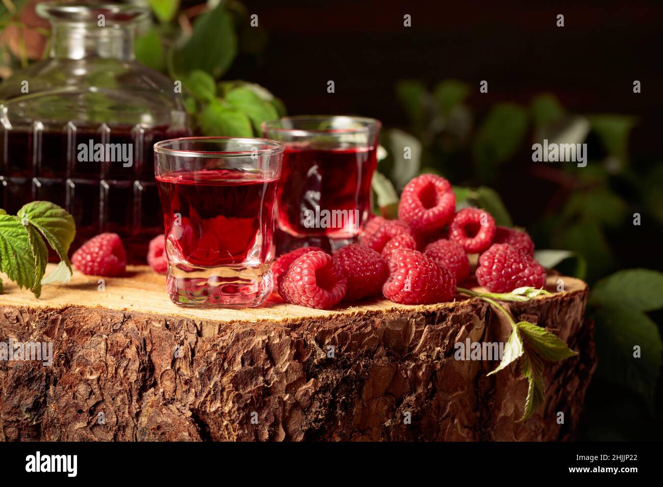 Raspberry liquor and fresh berries with leaves on a pine stump Stock ...