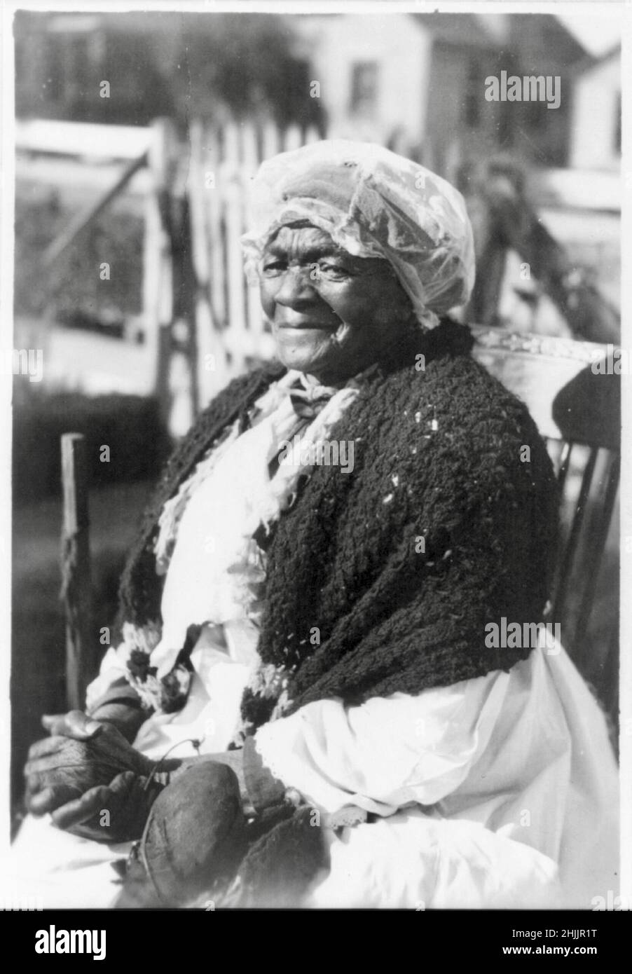 Mammy Prater wearing heavy shawl and cap sitting outside in rocking ...