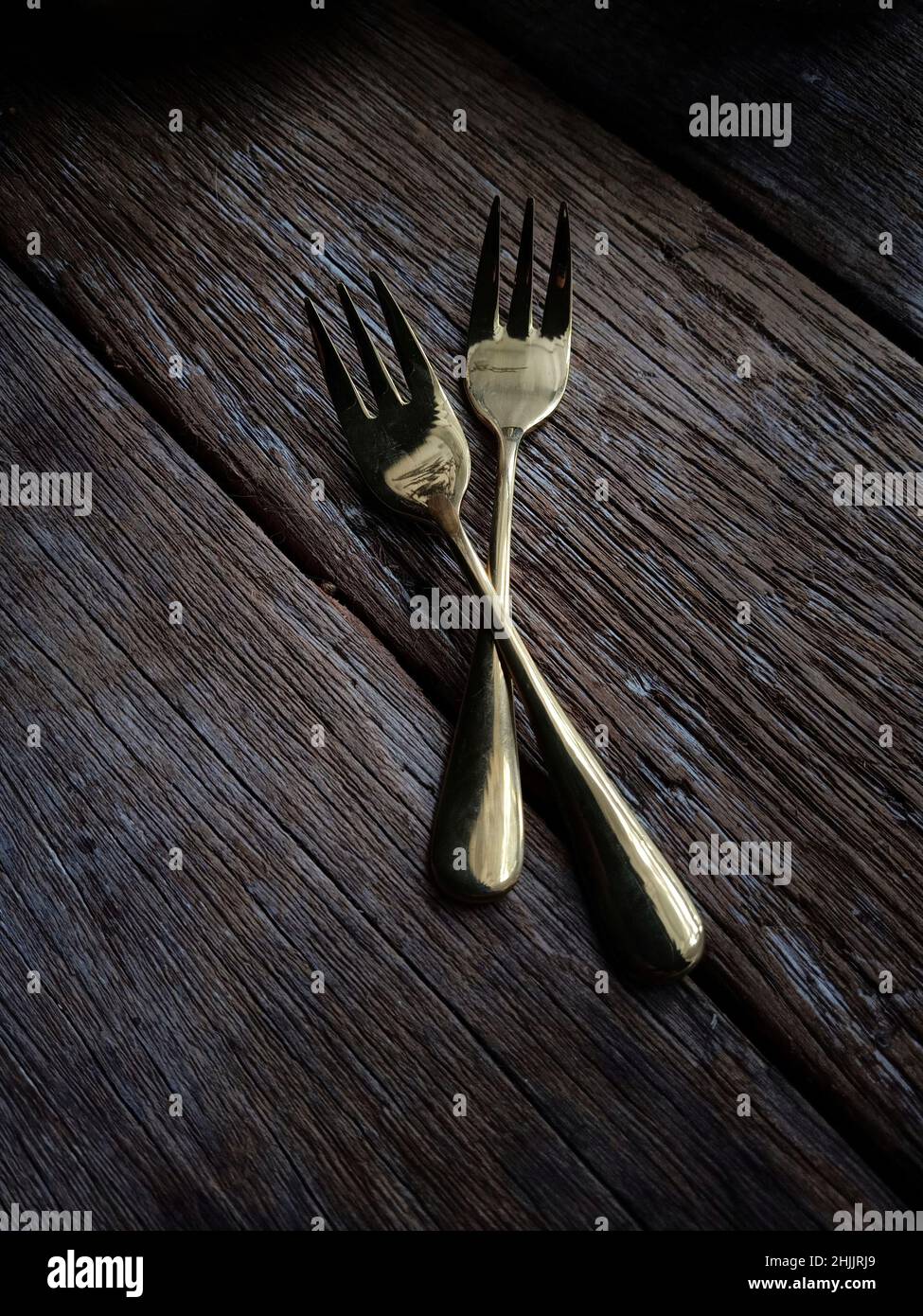 two crossed forks on a classic and rustic wooden table Stock Photo - Alamy