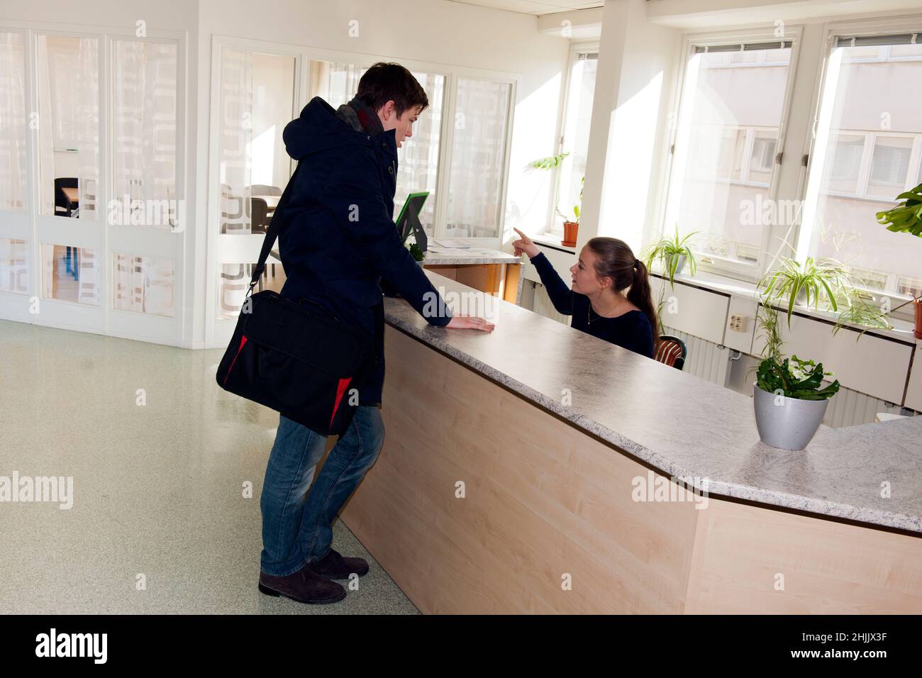 Guy asking a girl in a information desk something Stock Photo - Alamy