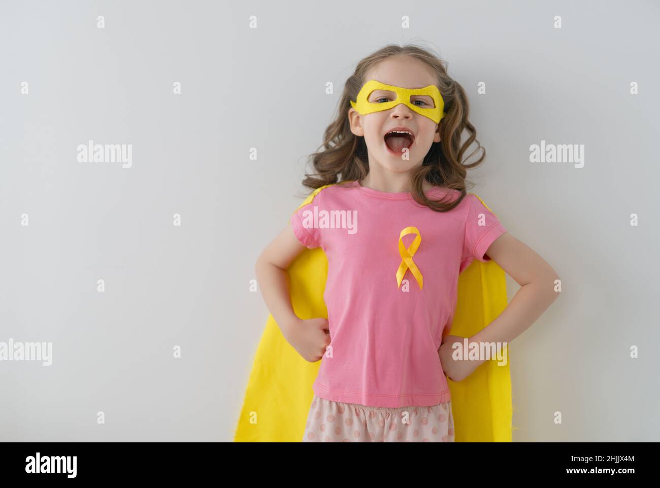 World Childhood cancer Day. Girl in superhero costume with golden ...