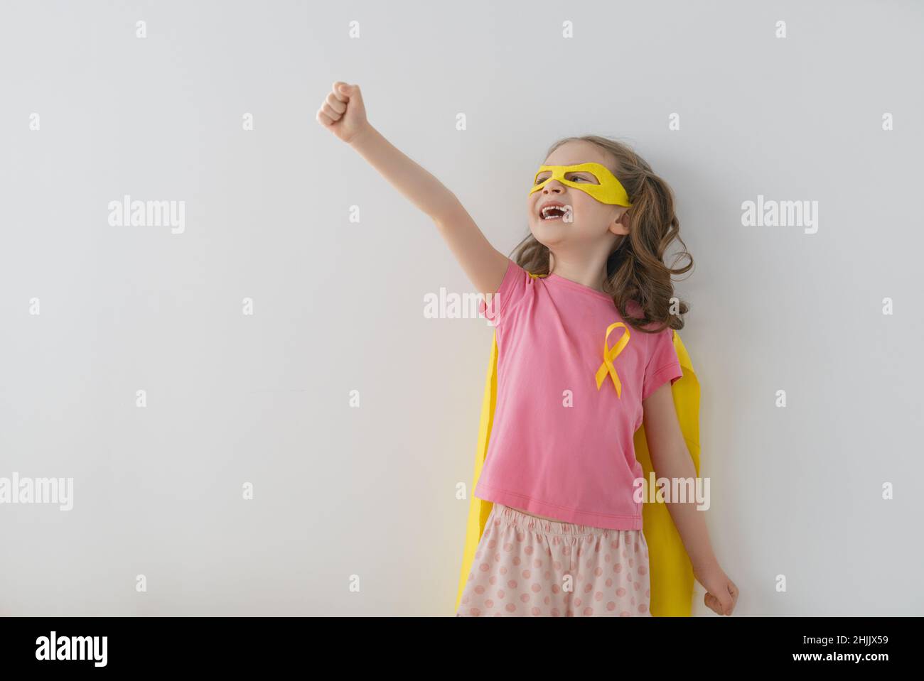 World Childhood cancer Day. Girl in superhero costume with golden ...