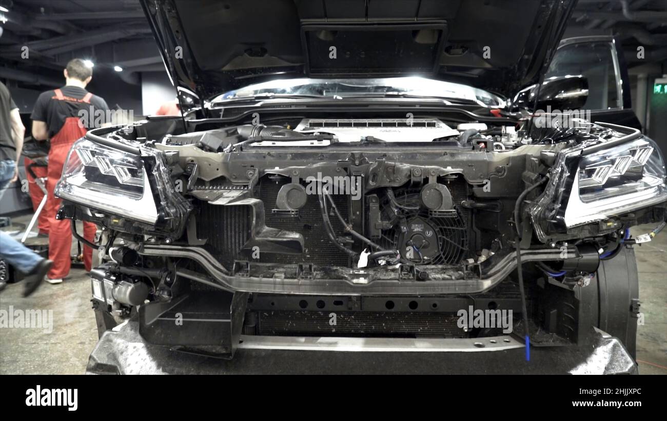 Assembling hood of car in automotive plant. Action. Close-up of details ...