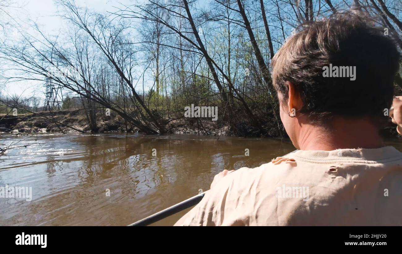 Man floating on raft with oar in river. Clip. Back view of man swimming ...