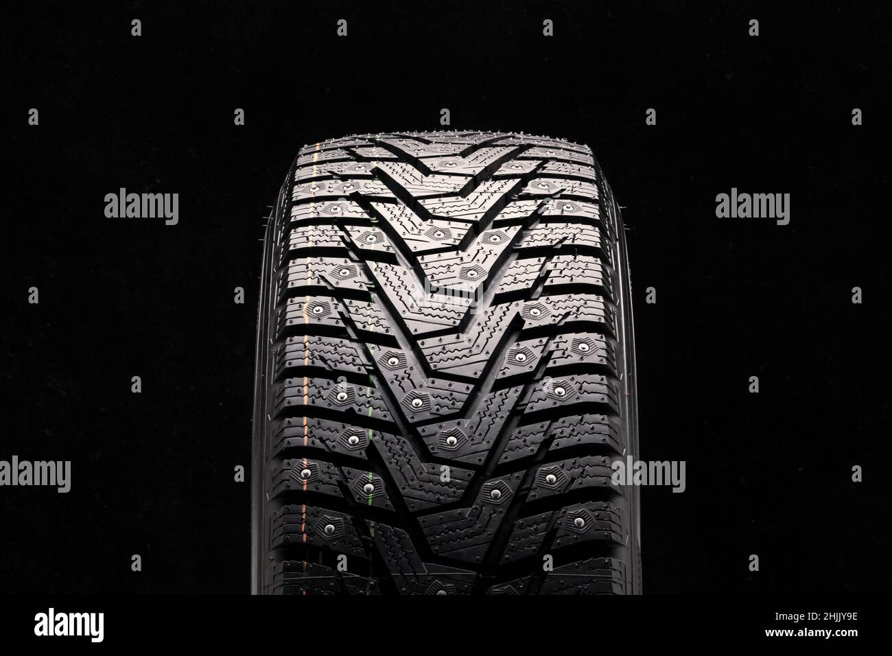 winter studded tire front view close-up on a black background tread ...