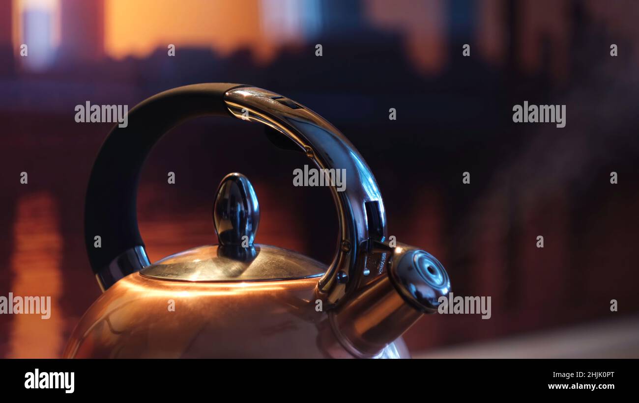 Polished kettle boiling on a gas stove in the kitchen in the evening ...
