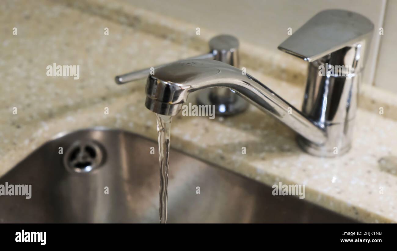 Pouring water from a tap in a kitchen. Concept. Close-up of water ...