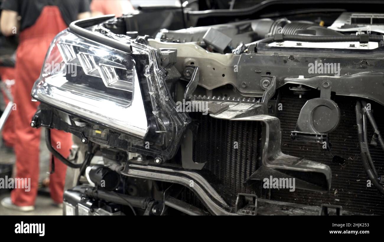 Assembling hood of car in automotive plant. Action. Close-up of details ...
