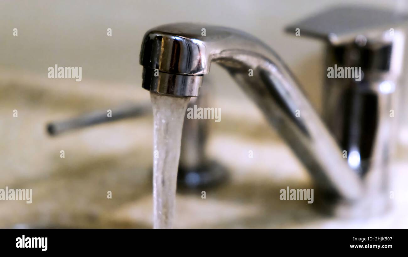 Pouring water from a tap in a kitchen. Concept. Close-up of water ...
