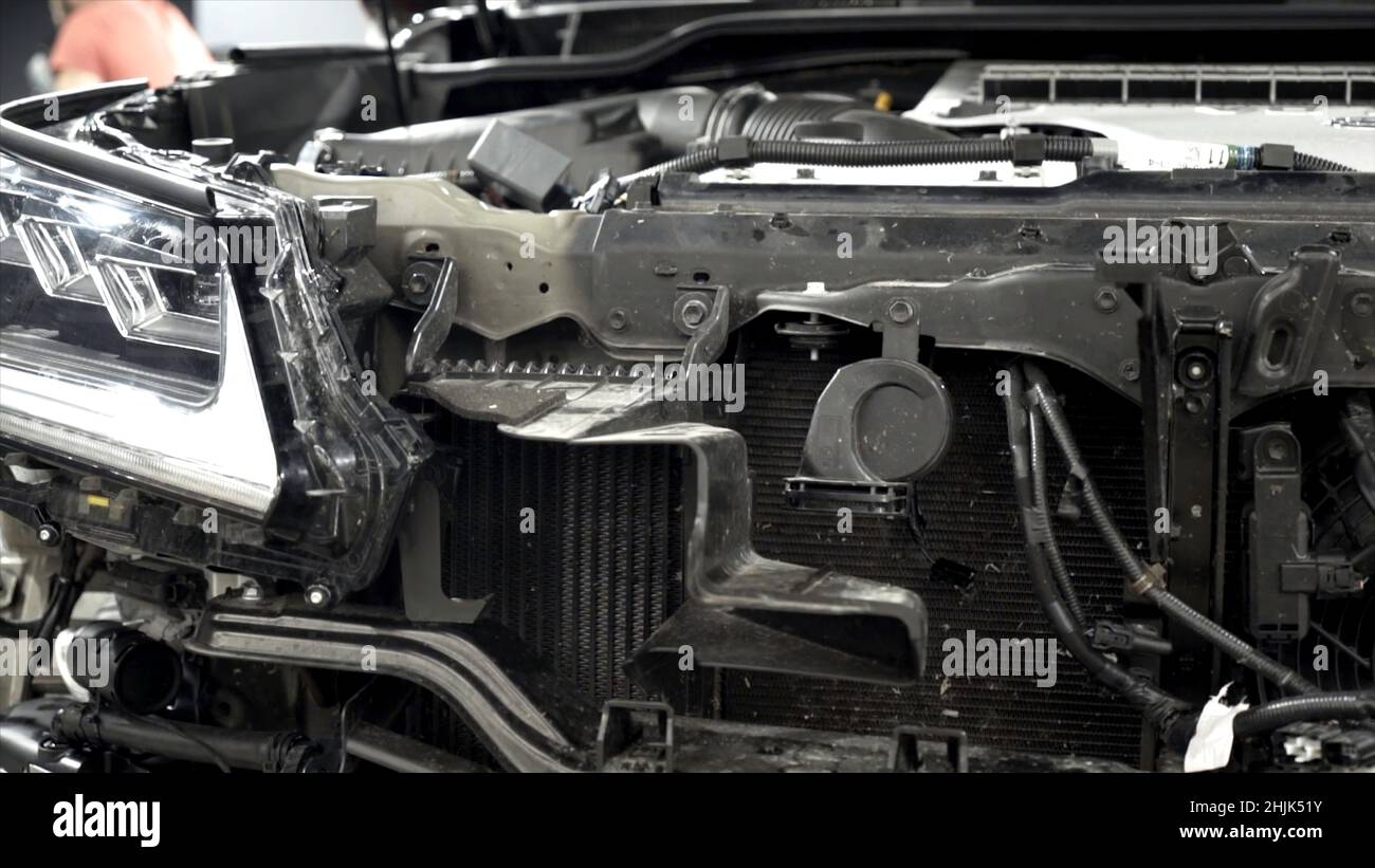 Assembling hood of car in automotive plant. Action. Close-up of details ...