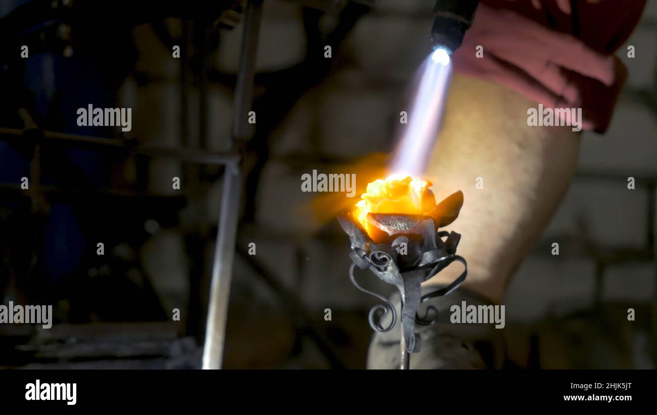 Blacksmith aligns leaves of iron rose and makes the final shape of the ...