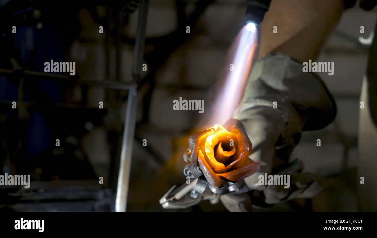 Blacksmith aligns leaves of iron rose and makes the final shape of the ...
