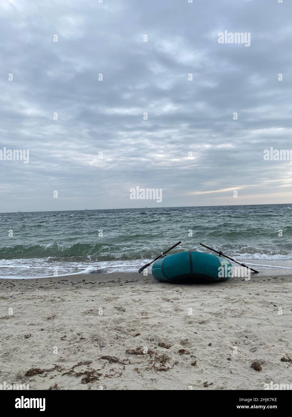 Vertical shot of a blue inflatable rowing boat on the sand at sea beach ...