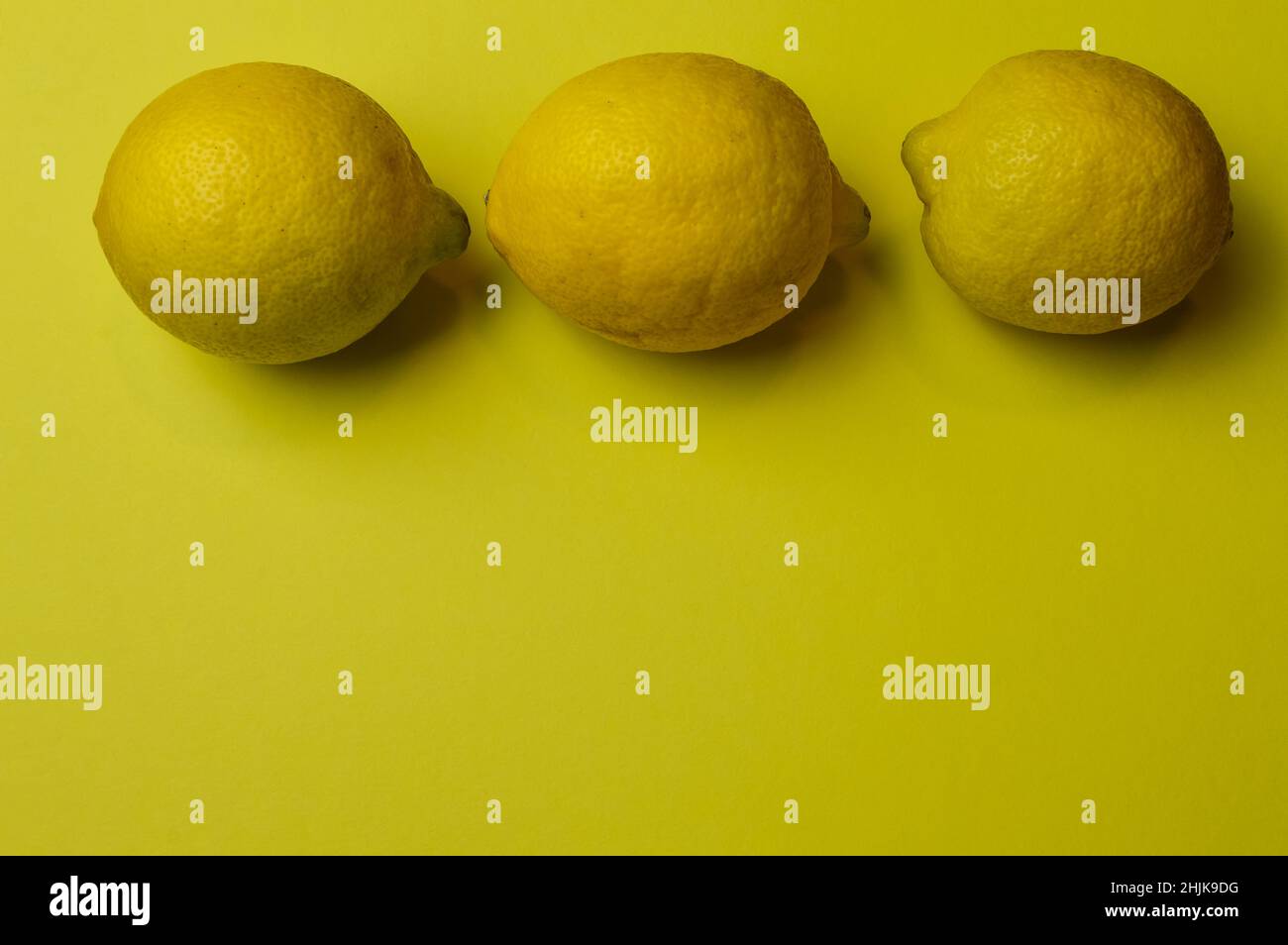 three organic lemons from sicily (siracusa) on a light yellow paper ...