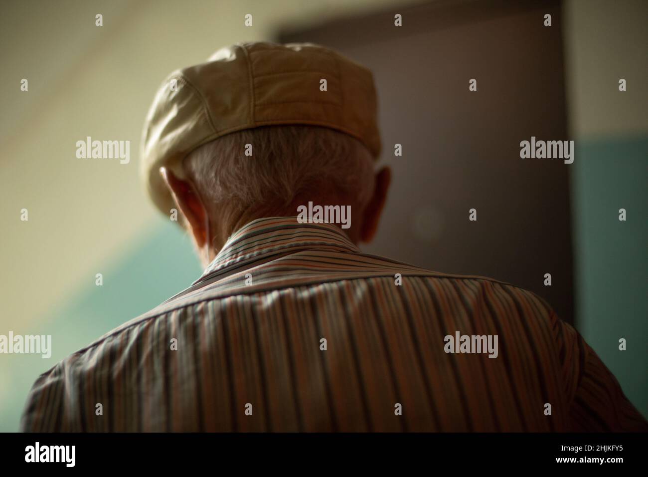 Old man from behind. Man in cap in entrance of apartment building ...
